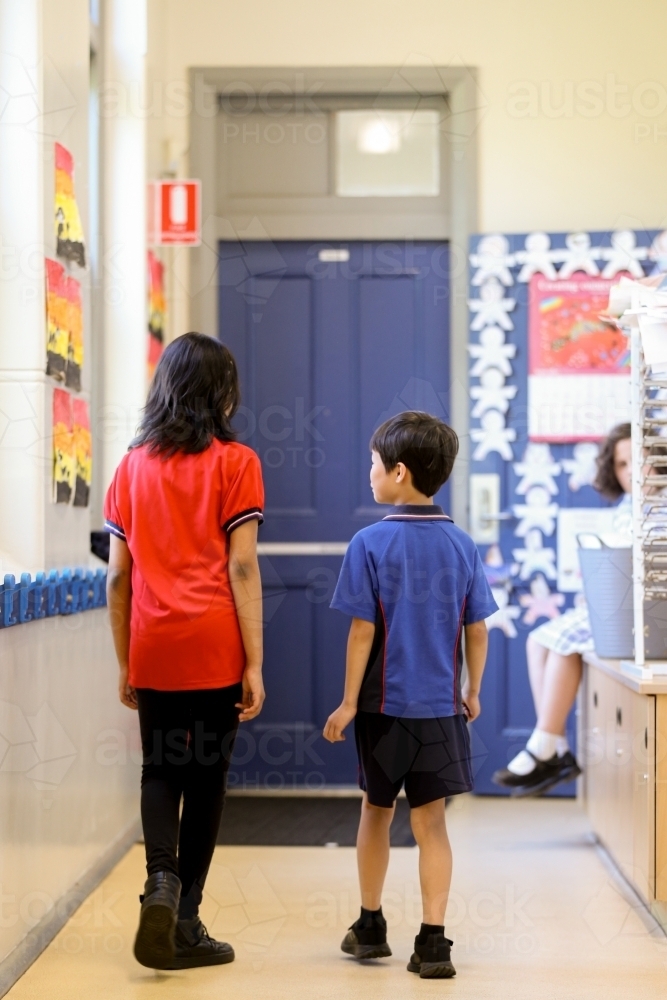 Image of Two school students walking away in the corridor - Austockphoto