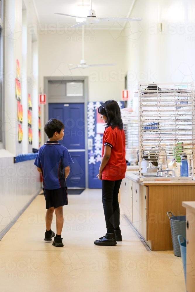 Image of Two school students walking away in the corridor - Austockphoto