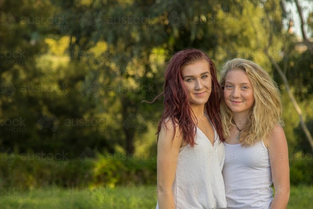 Image of Two sisters standing together in the backyard - Austockphoto