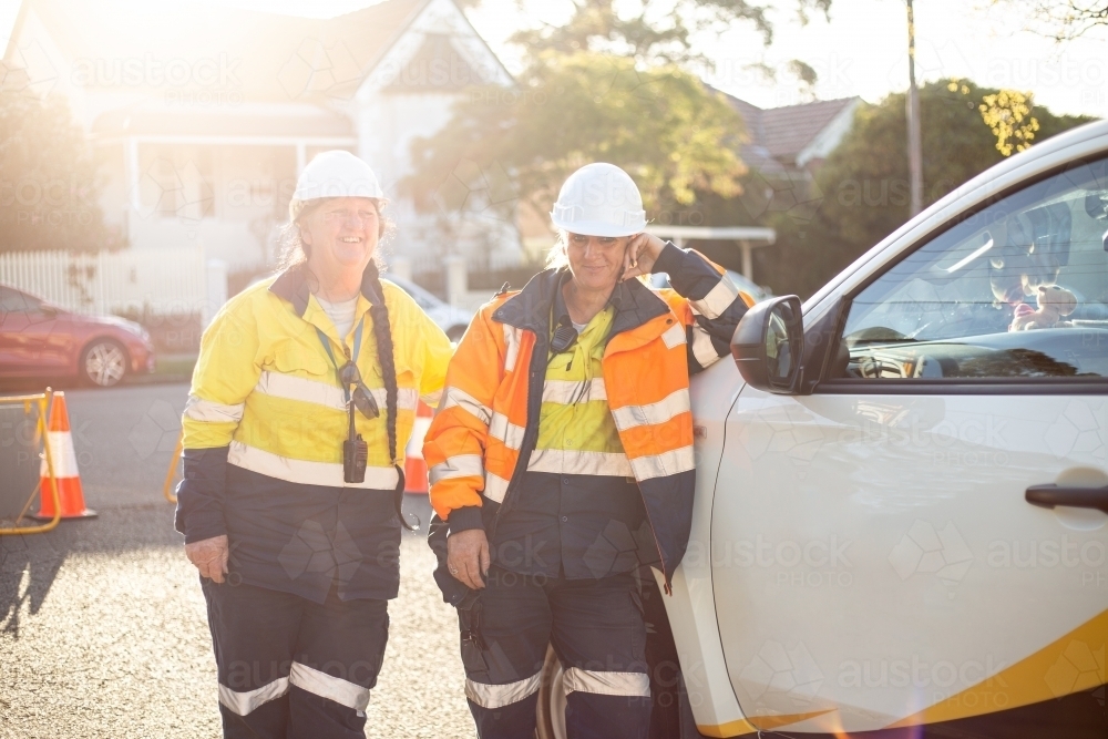 Image of Two smiling women road workers with white helmet leaning on a ...