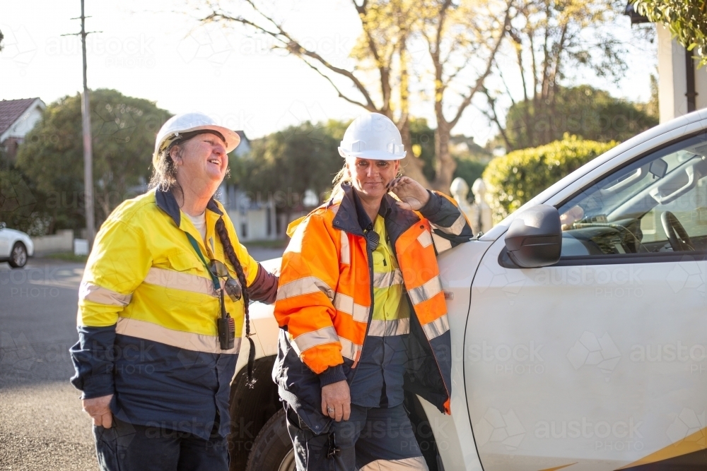 Image of Two smiling women road workers with white helmet leaning on a ...