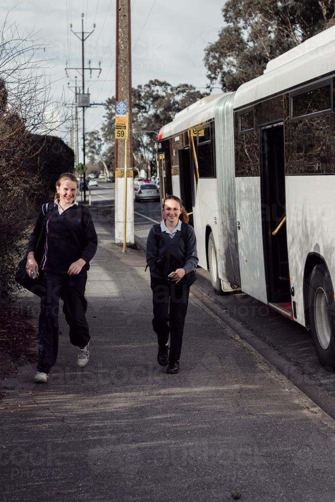 Image of two teen high school students getting off the bus after school ...