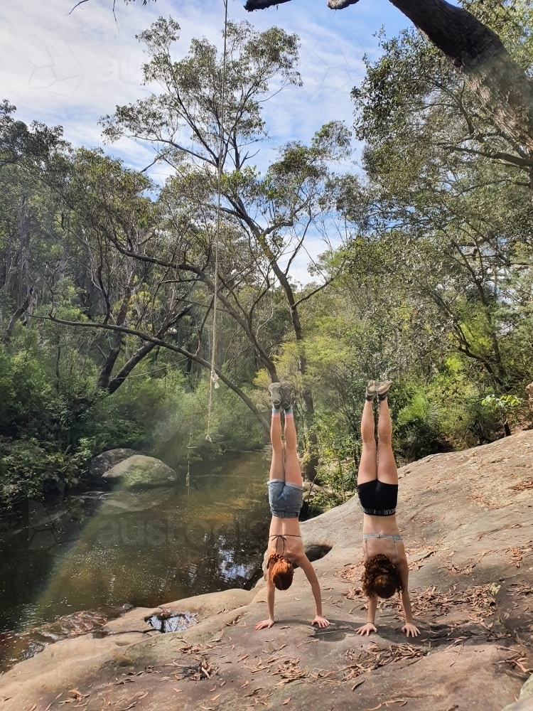 Image of Two teenagers doing a handstand by a waterhole - Austockphoto