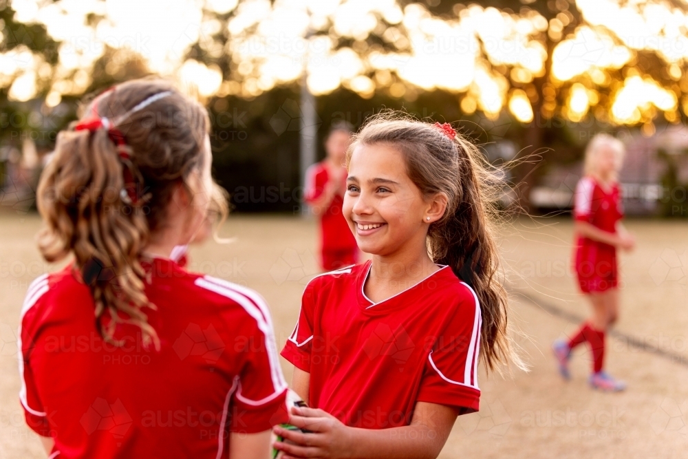 Image of Two tween football players standing together at a sports oval ...