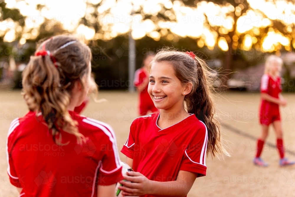 Image of Two tween football players standing together at a sports oval ...