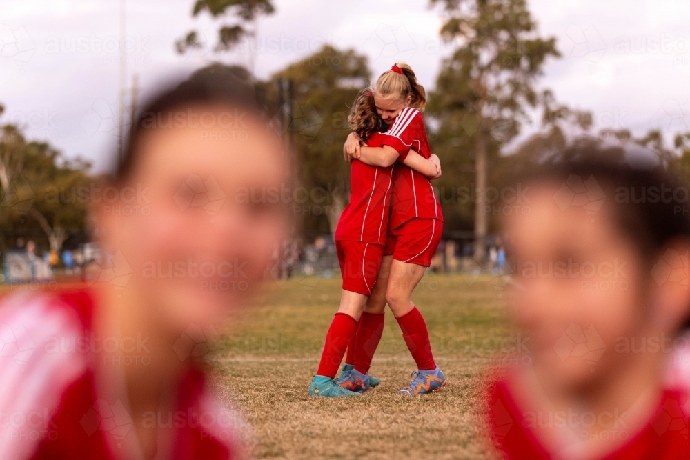 Image of Two tween girls in a football team hug to celebrate a win ...