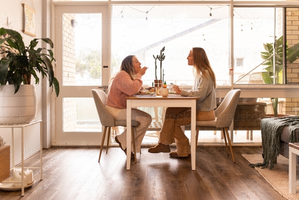 Image of Two women eating meal together at home - Austockphoto
