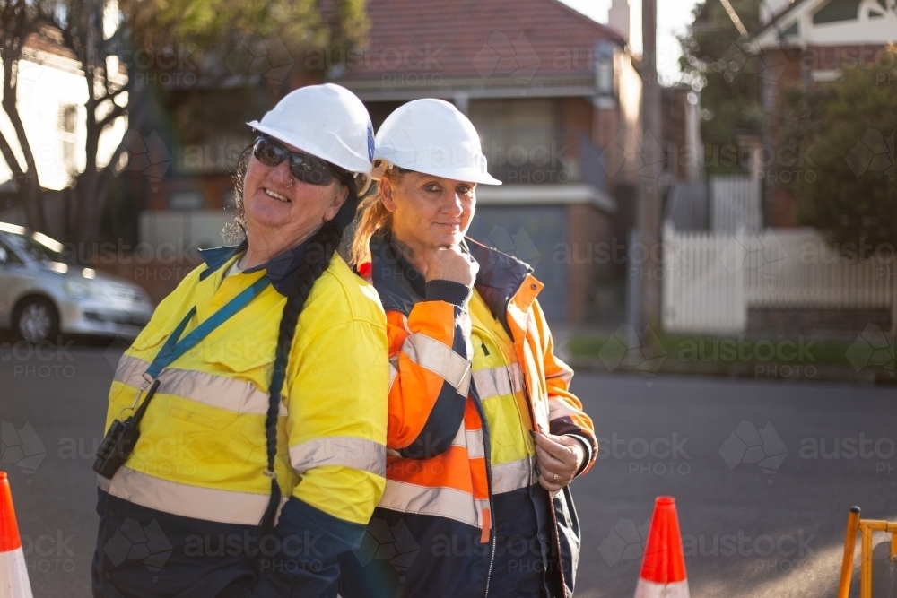 Image of Two women road workers wearing white helmet with high vis ...