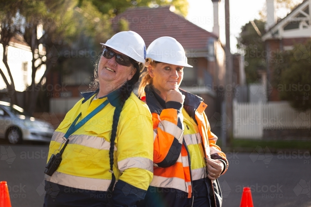 Image of Two women road workers wearing white helmet with high vis ...