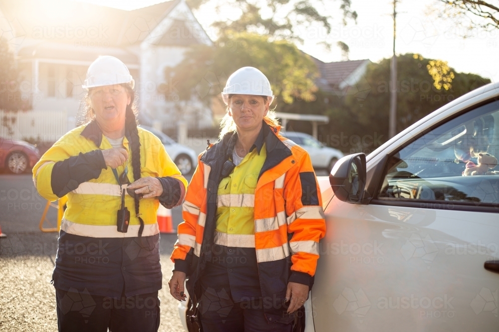 Image of Two women road workers wearing white helmet with orange and ...