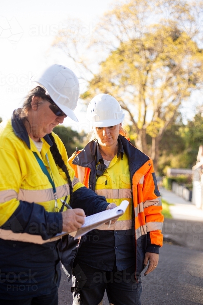 Image of Two women road workers with white hat wearing yellow and ...