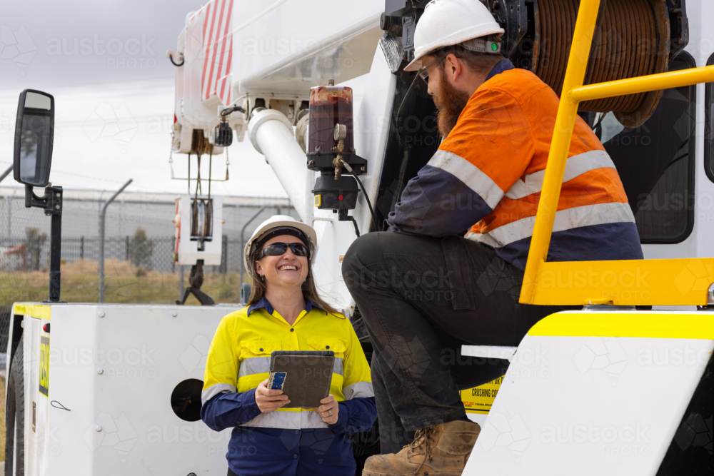Image of Two workers wearing high visibility clothing man sitting on ...