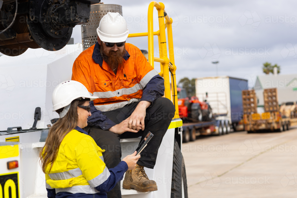 Image of Two workers wearing high visibility clothing man sitting on ...