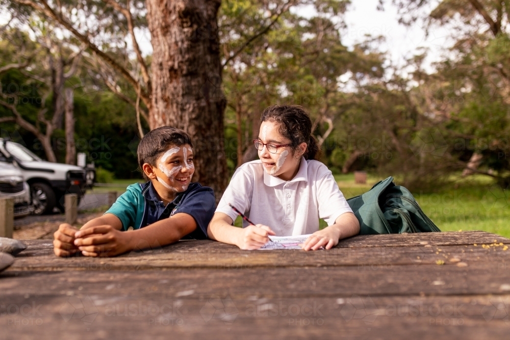 Image of Two young Aboriginal children sitting at a table outdoors ...