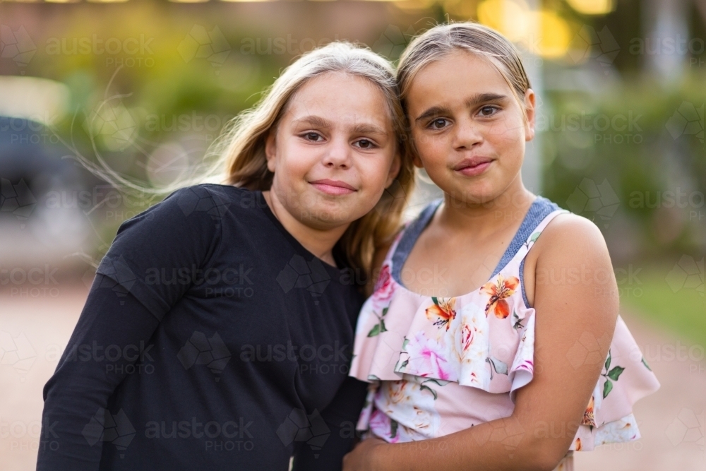 Image of two young aboriginal girls outside with heads together ...