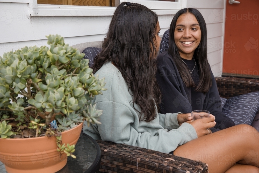 Image of Two young Aboriginal women sitting together - Austockphoto