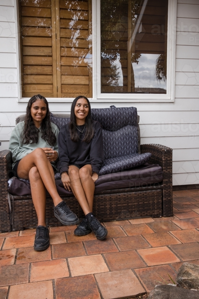 Image of Two young Aboriginal women sitting together - Austockphoto