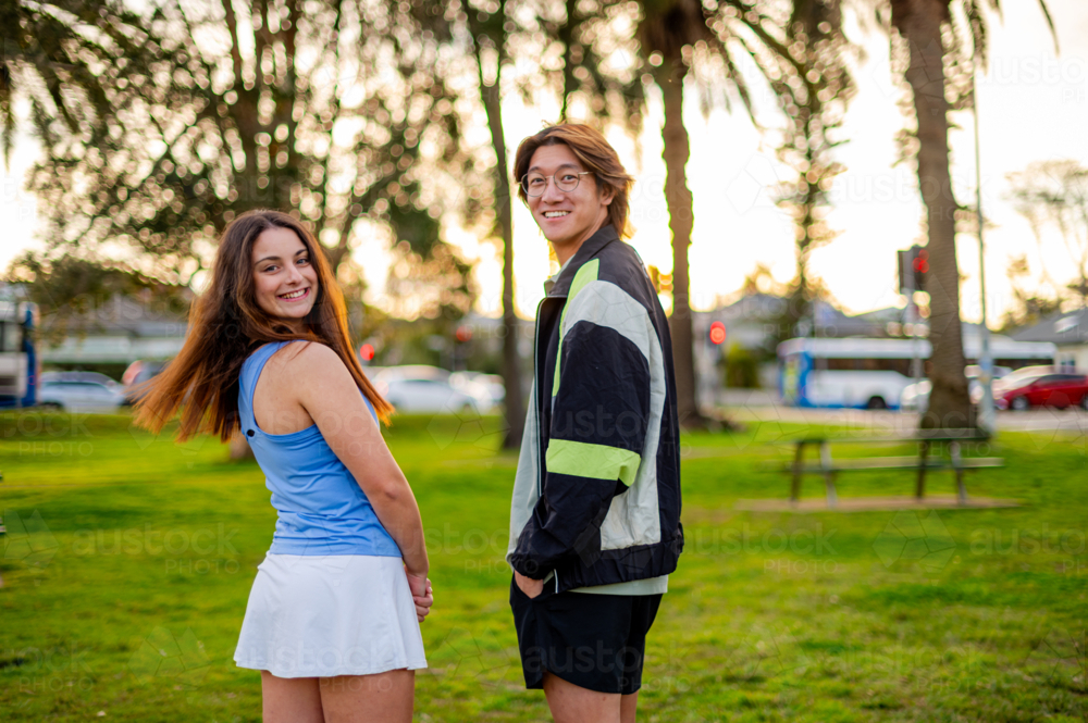 Image of Two young adults smile at each other in a park during a sunny ...