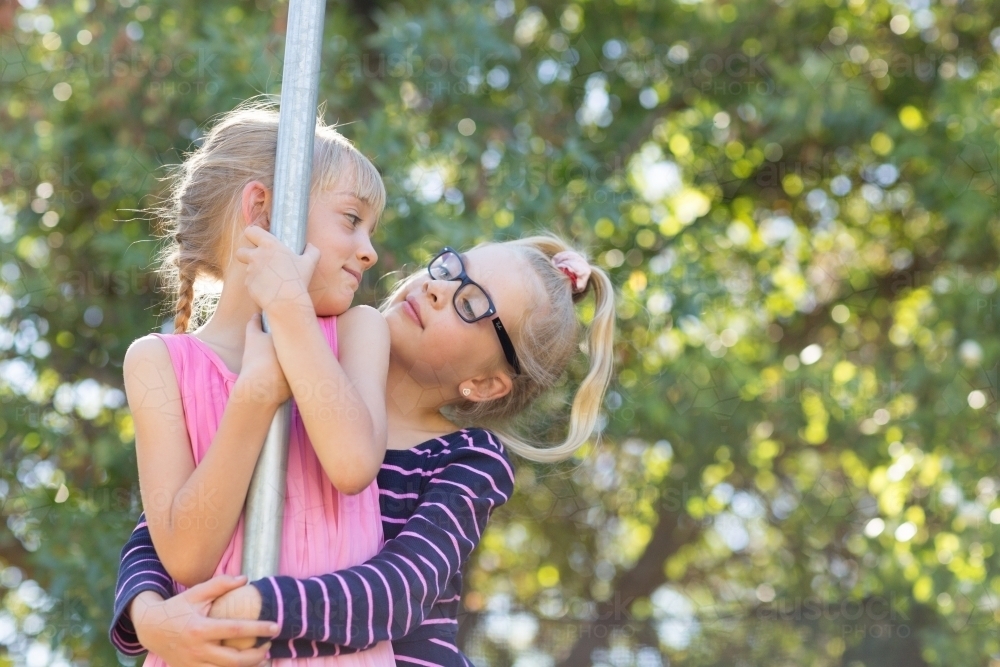 Image of Two young blonde girls with arms around each other - Austockphoto
