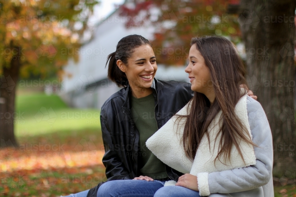 Image of Two young female friends sitting together in an outdoor ...