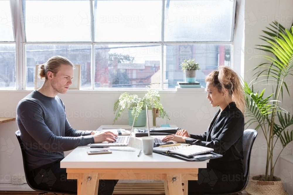Image of Two young people working at a shared desk horizontal ...