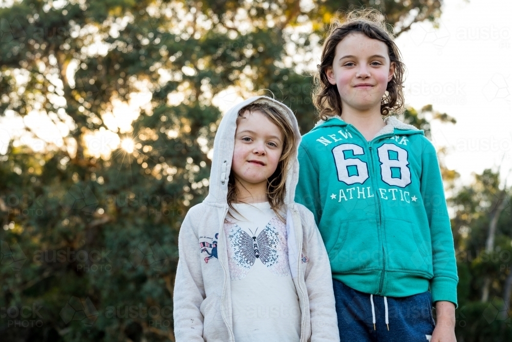 Image of Two young sisters standing side by side at sunrise in a rural ...