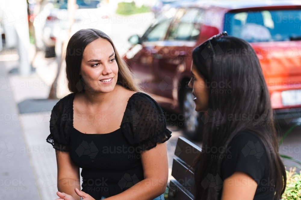 Image of two young women sitting and talking - Austockphoto