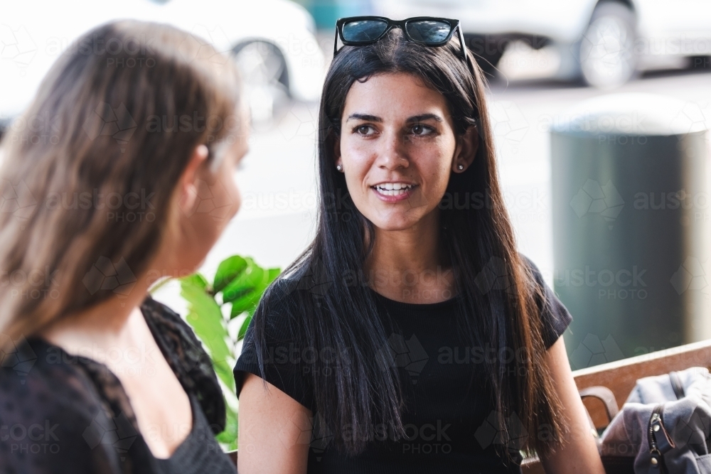 Image of two young women sitting and talking - Austockphoto