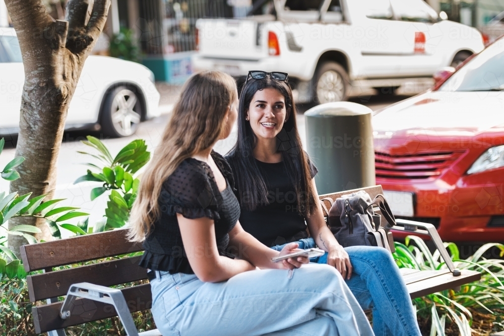 Image of two young women sitting and talking - Austockphoto