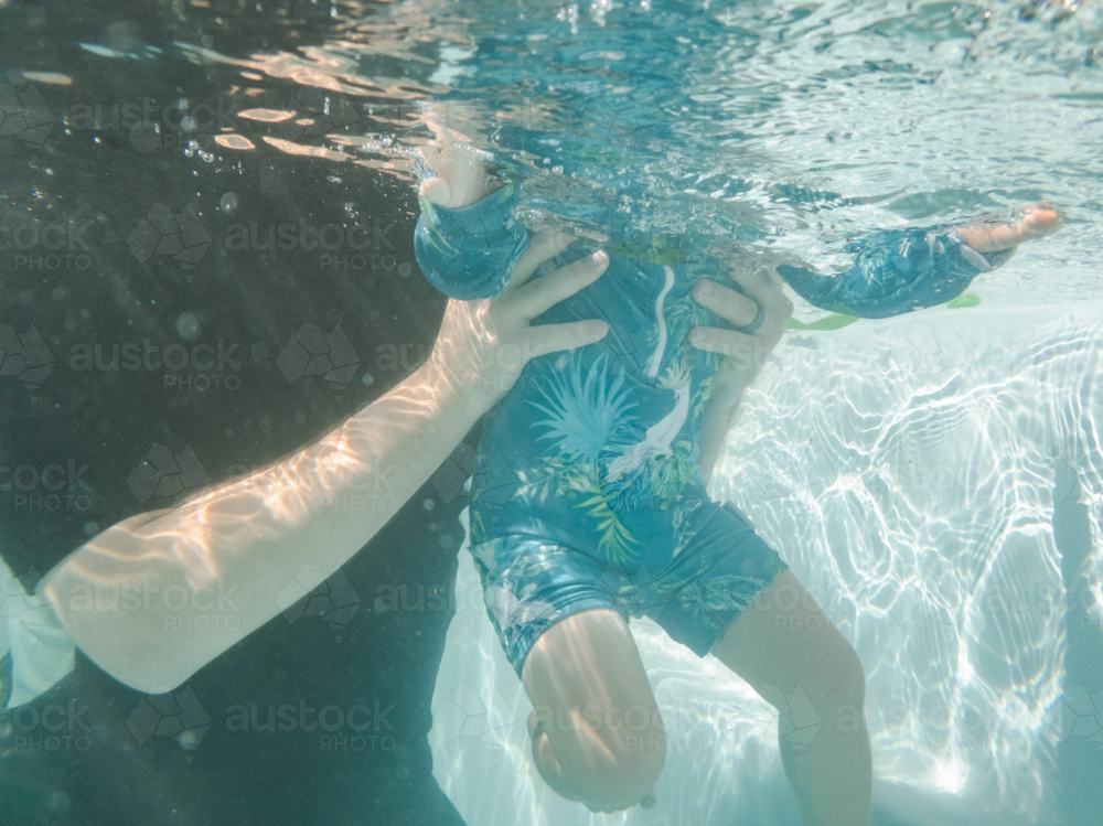 Image of underwater view of man helping toddler kid swim through water ...