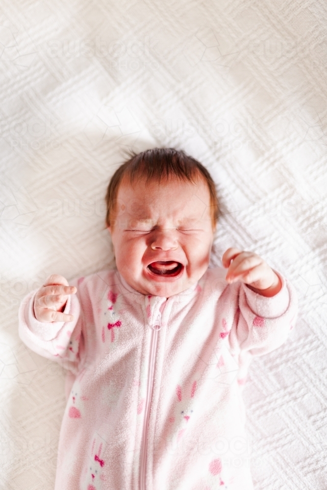 Image of Unhappy baby on white crying reaching arms out - Austockphoto
