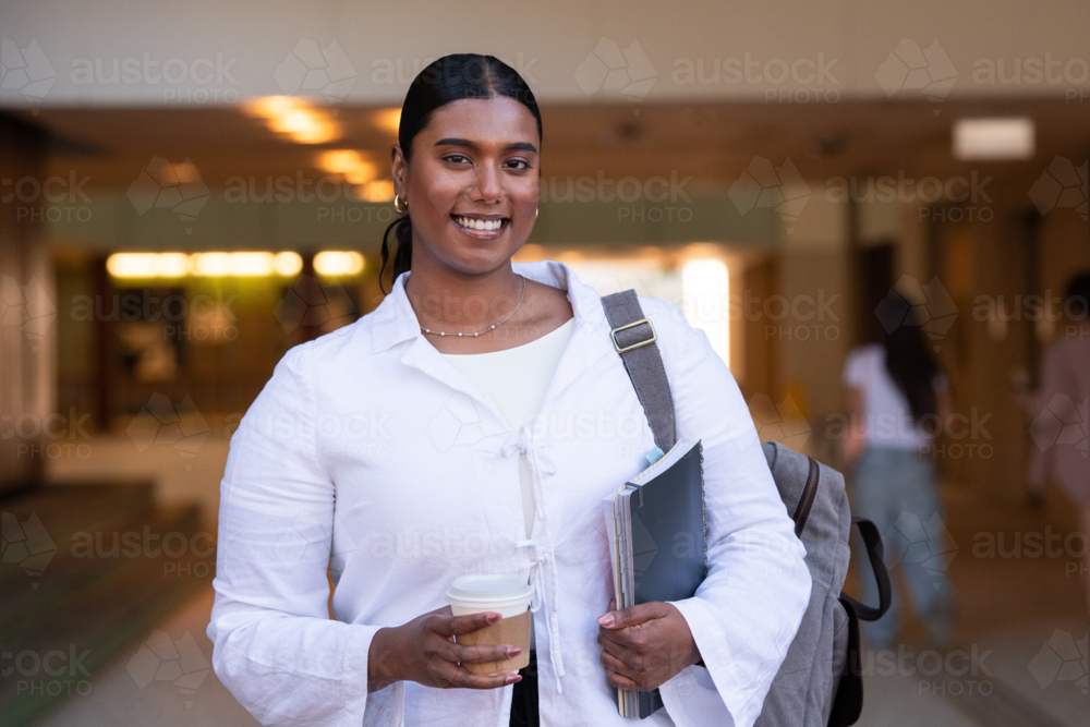 Image of uni student on campus, with backpack, books and a coffee ...