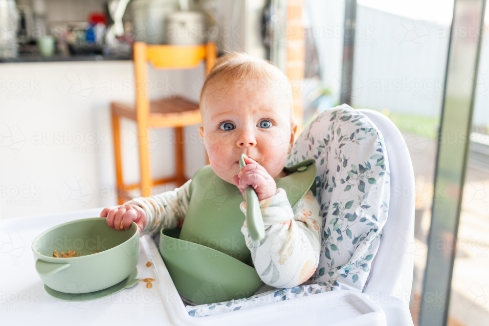Image of Unsure baby with wide eyes tasting weetbix food for breakfast ...