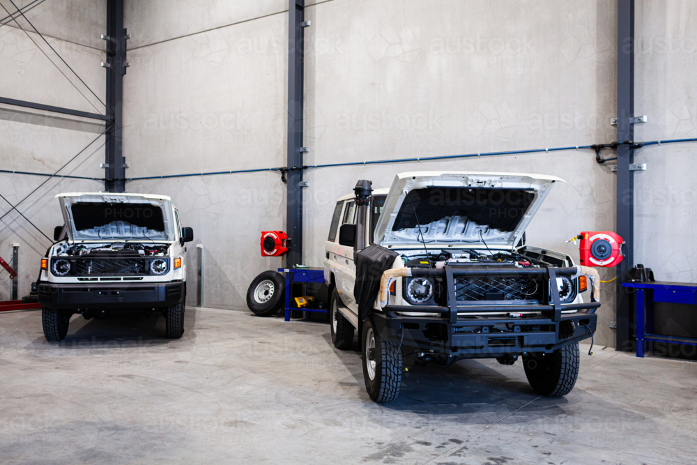 Image of Utility vehicles with bonnets open parked inside workshop ...
