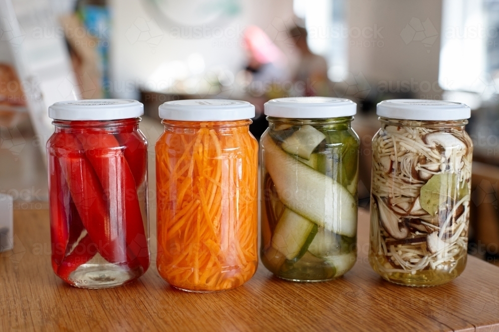 Image of Variety of pickle jars lined up on counter in cafe - Austockphoto