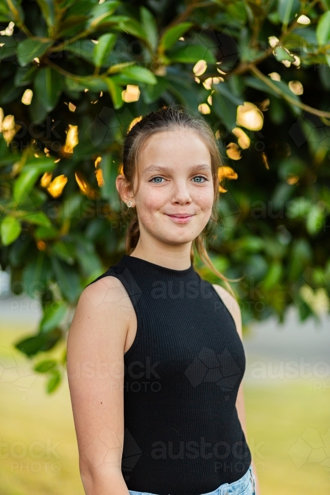 Image of vertical portrait of smiling young tween girl against natural ...