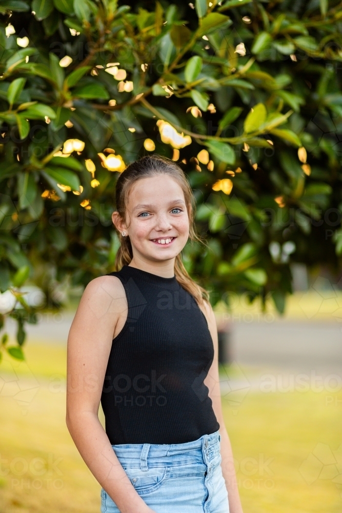Image of vertical portrait of smiling young tween girl against natural ...
