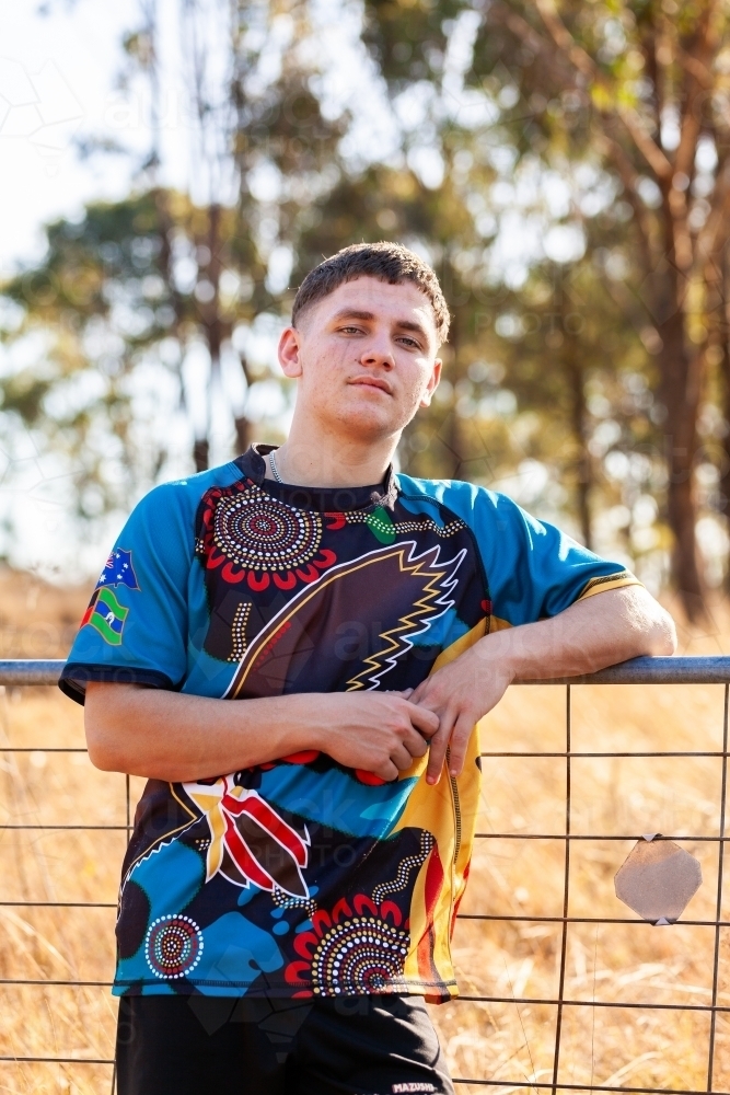 Image of Vertical portrait of teenage Aboriginal boy leaning on gate ...