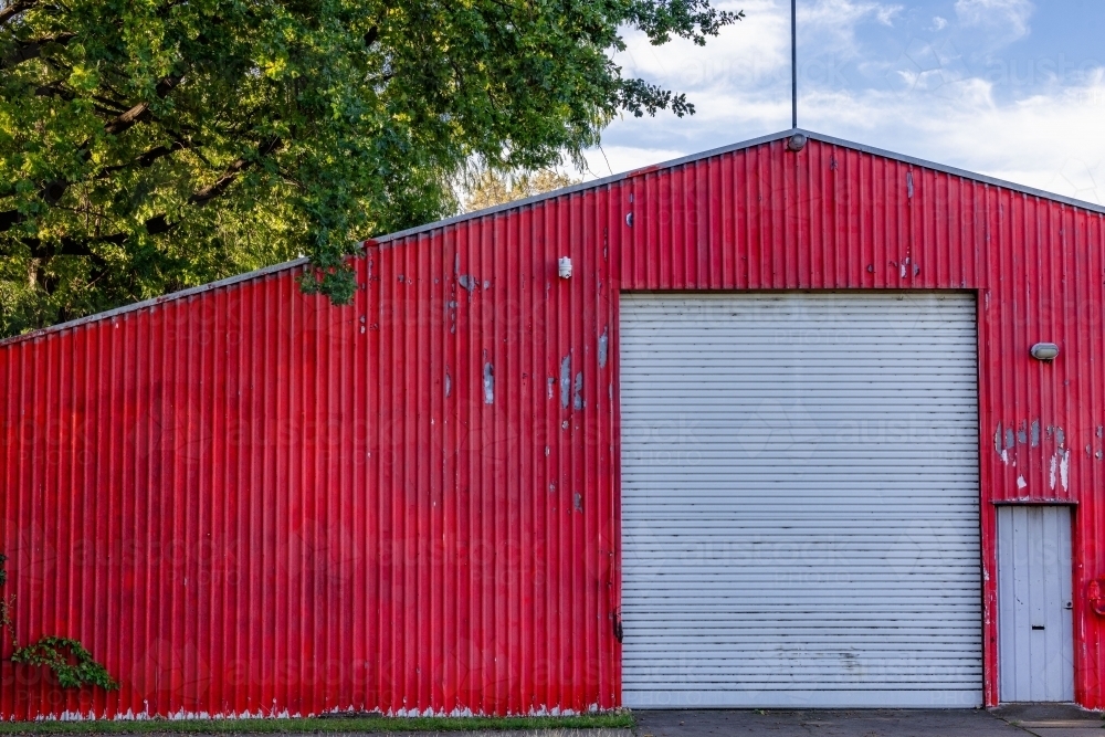 Image of Vibrant red shed with large white door - Austockphoto