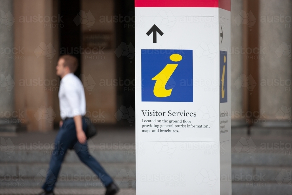 Image of Visitor services sign with office worker walking in background ...