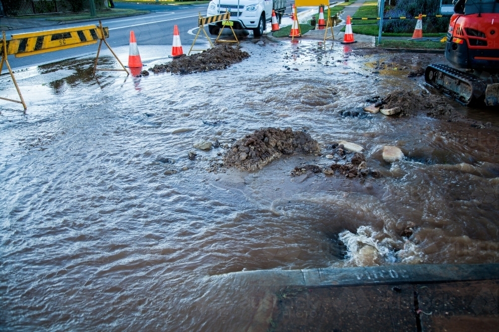Image of Water and mud over a town road from a broken water main ...