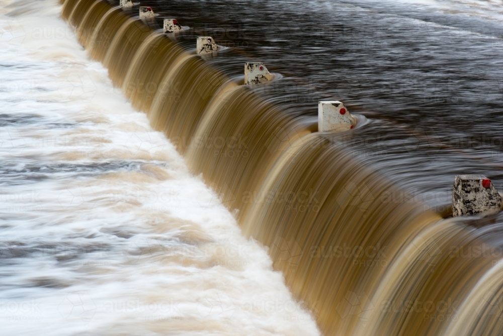 Image of Water pouring over a weir during a flood - Austockphoto
