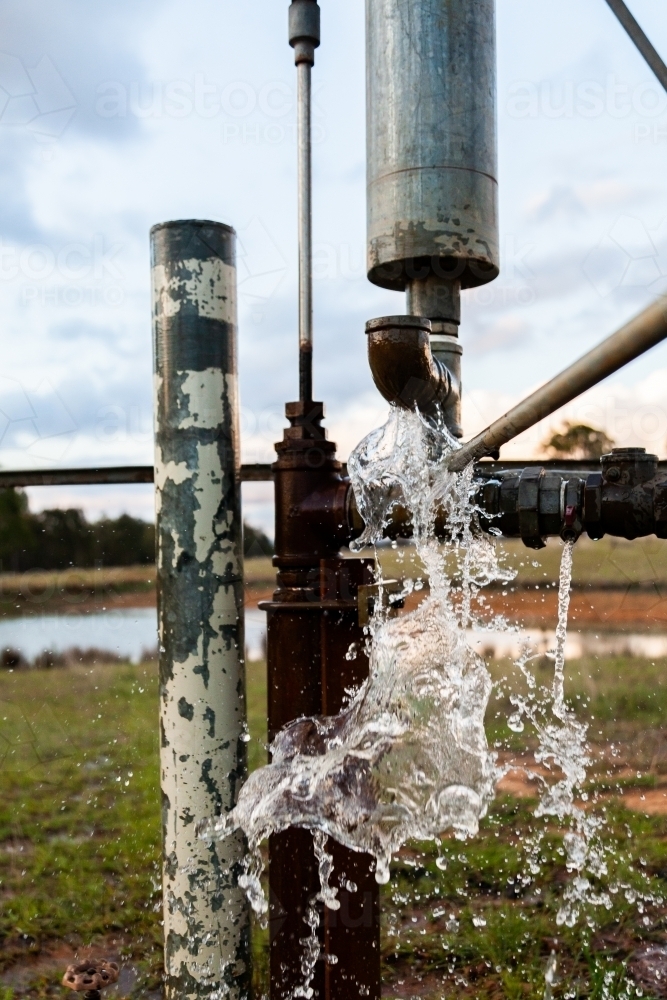 Image of Water splashing from windmill pump on farm - Austockphoto
