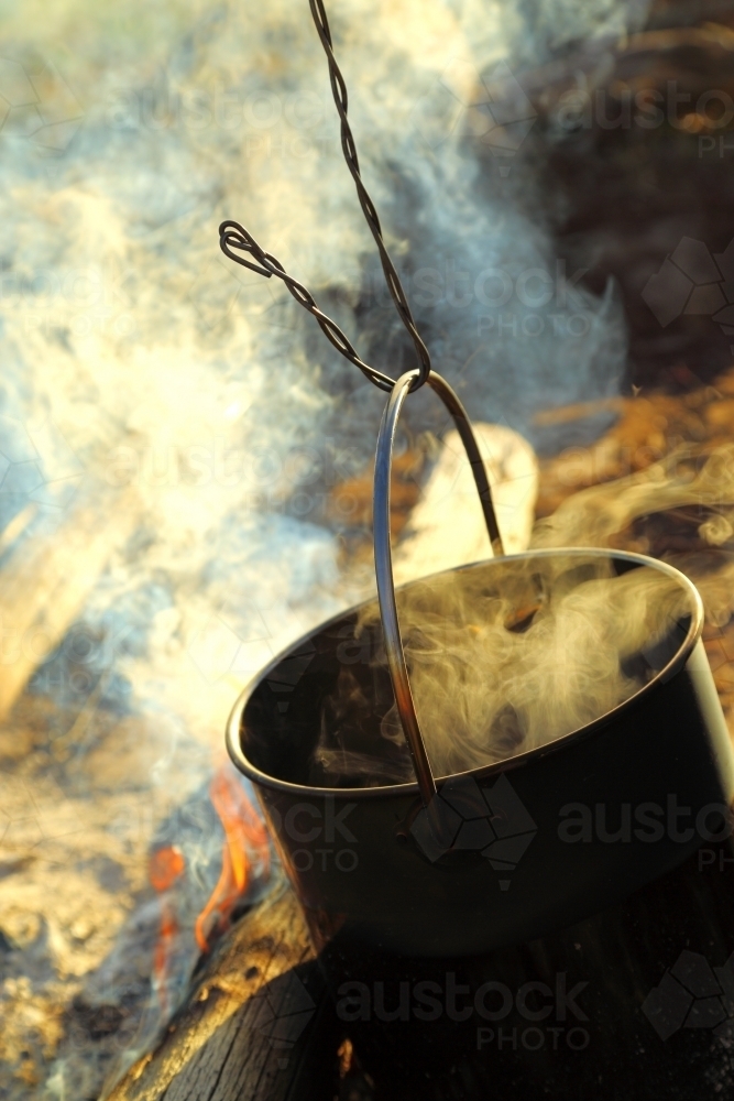 Image of Water steaming in the black billy billycan over a campfire ...