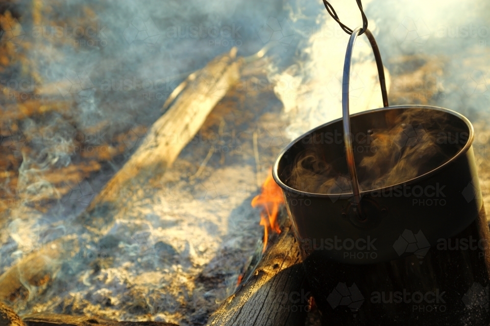 Image of Water steaming in the black billy over a campfire - Austockphoto