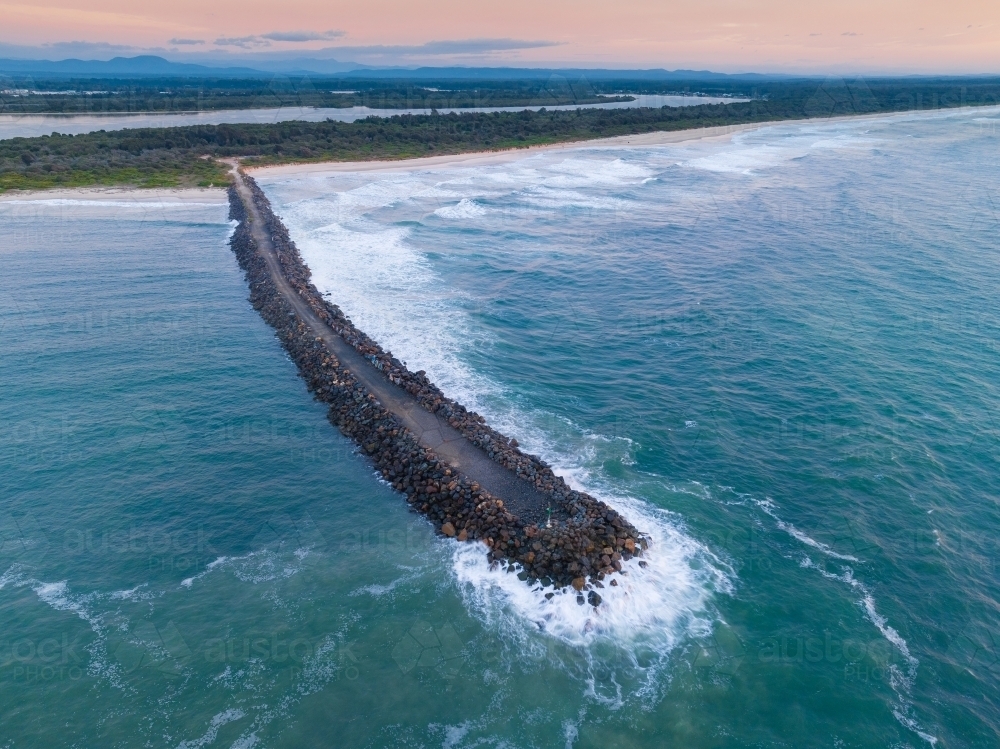 Image of waves washing over a long narrow breakwater stretching out ...