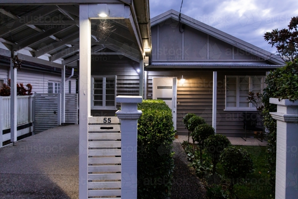 Image of weatherboard house with lights on at the front porch at night ...