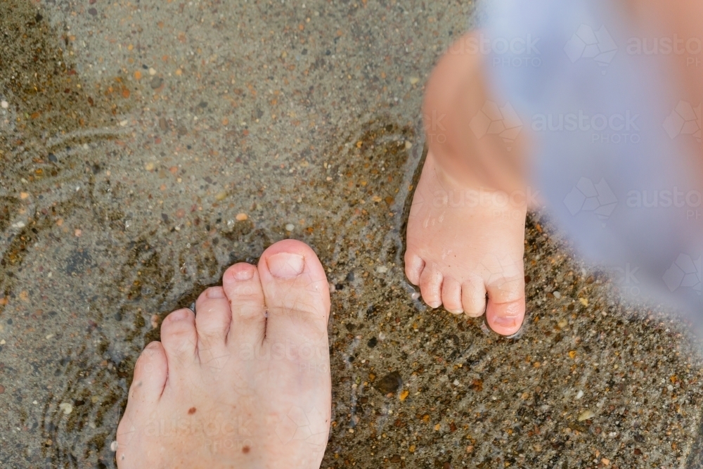 Image of wet feet in rain puddle mum and toddler toes - Austockphoto