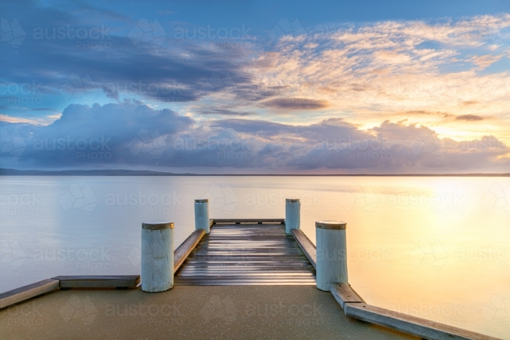 Image of Wharf on still lake at sunrise - Austockphoto