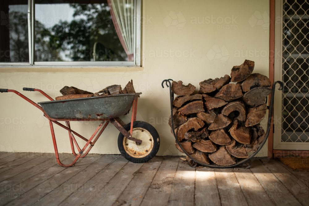 Image of Wheelbarrow and stack of wood on verandah of country home ...